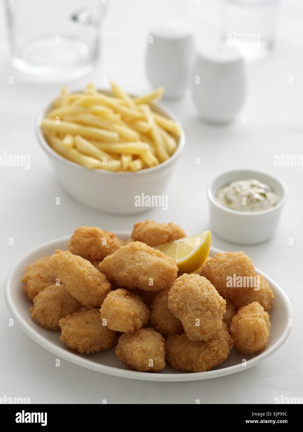 Breaded fish nuggets chips and peas in separate bowls tartare sauce ...