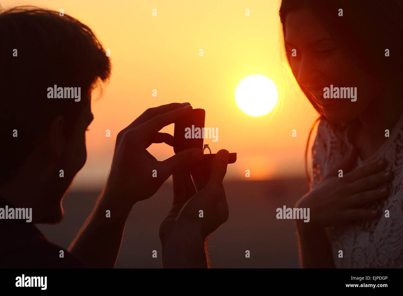 Back light of a couple proposal of marriage on the beach at sunset ...