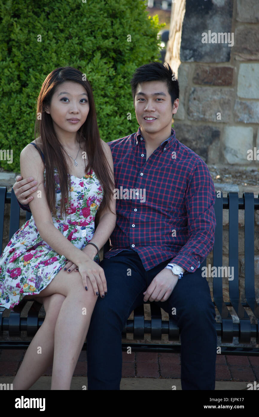 Romantic Asian couple , a man and woman, sitting outdoors on a park ...