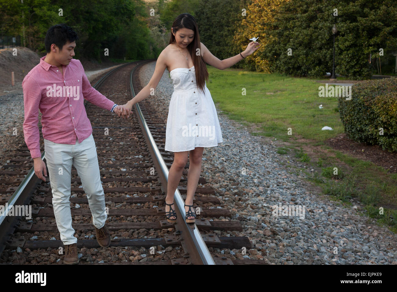 Romantic Asian couple playing outside on railroad tracks, being ...
