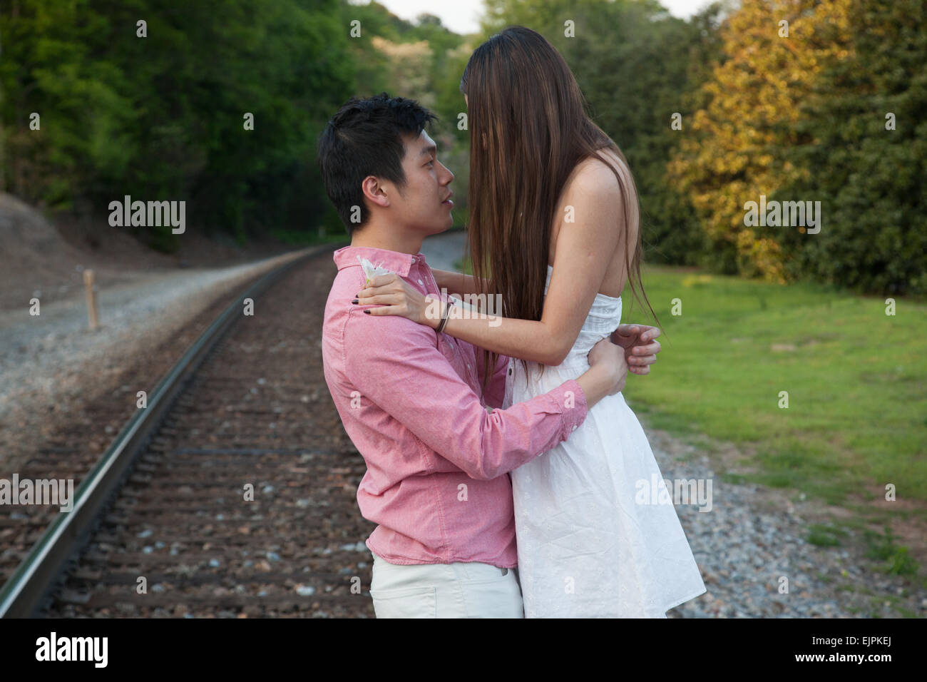 Romantic Asian couple playing outside being affectionate and smiling ...