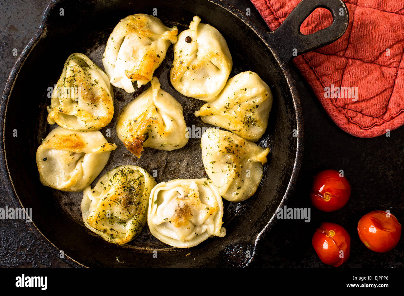 Fried Russian pelmeni with meat in a frying pan. Near potholder and ...