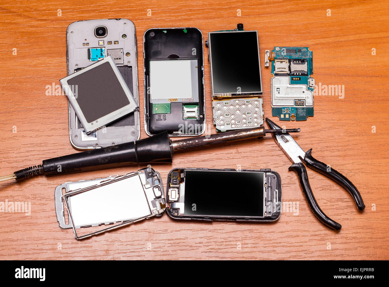 broken phones and soldering tool that is pliers Stock Photo - Alamy