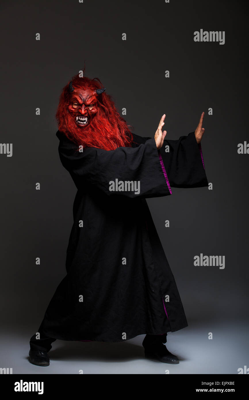 halloween monster with red face on dark background, pushing something ...