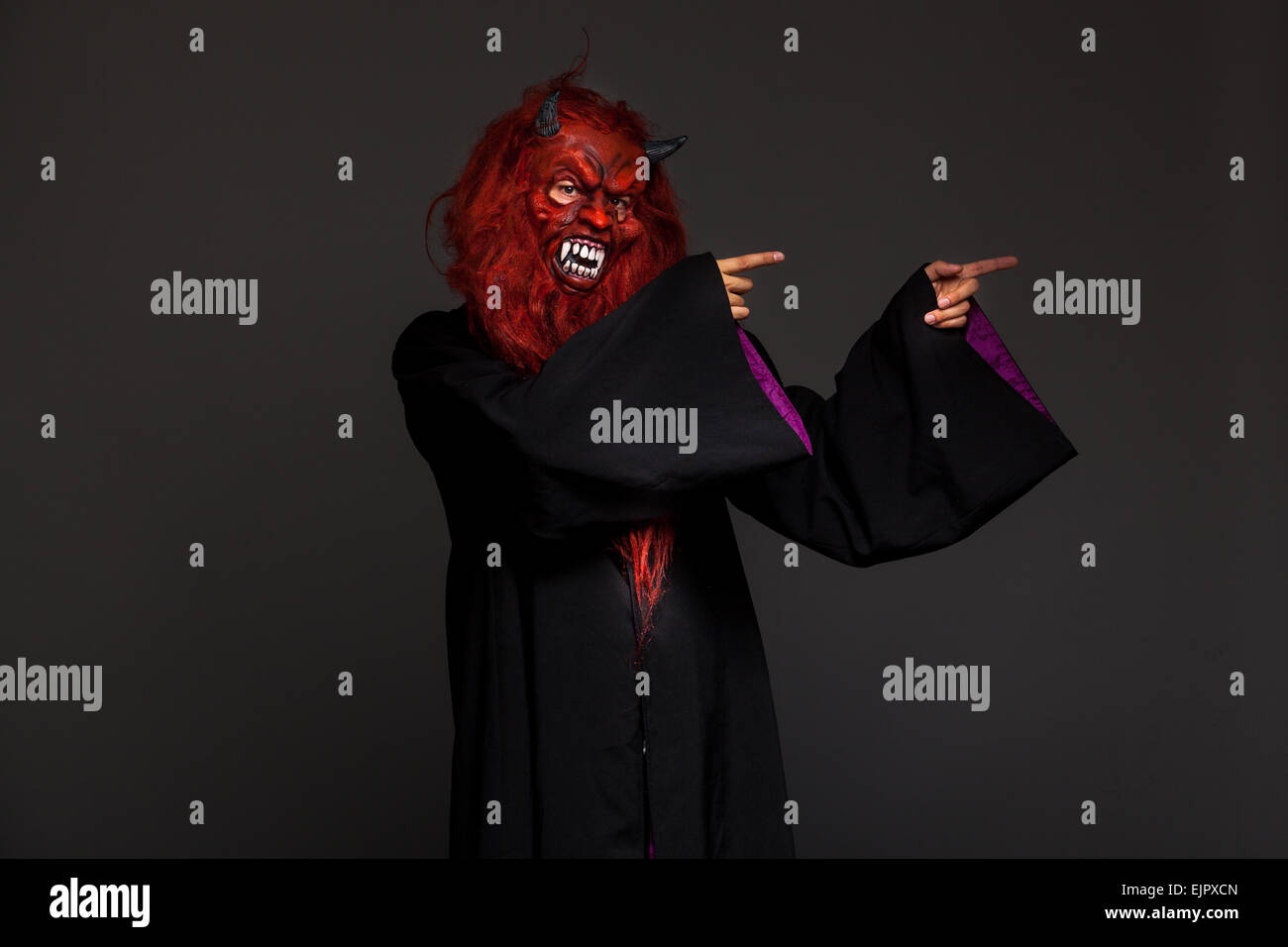 halloween monster with red face on dark background, pointing directions ...