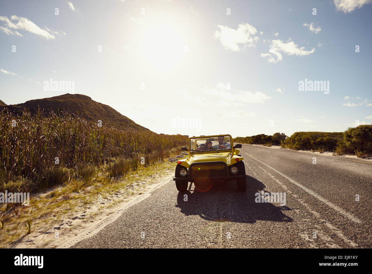 Outdoor shot of young couple in a car on open road on a summer day ...