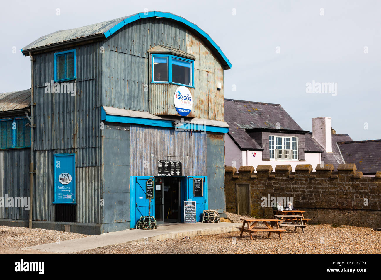 Elderly couple enjoy a hot drink outside a fish cafe and shop on Hythe ...