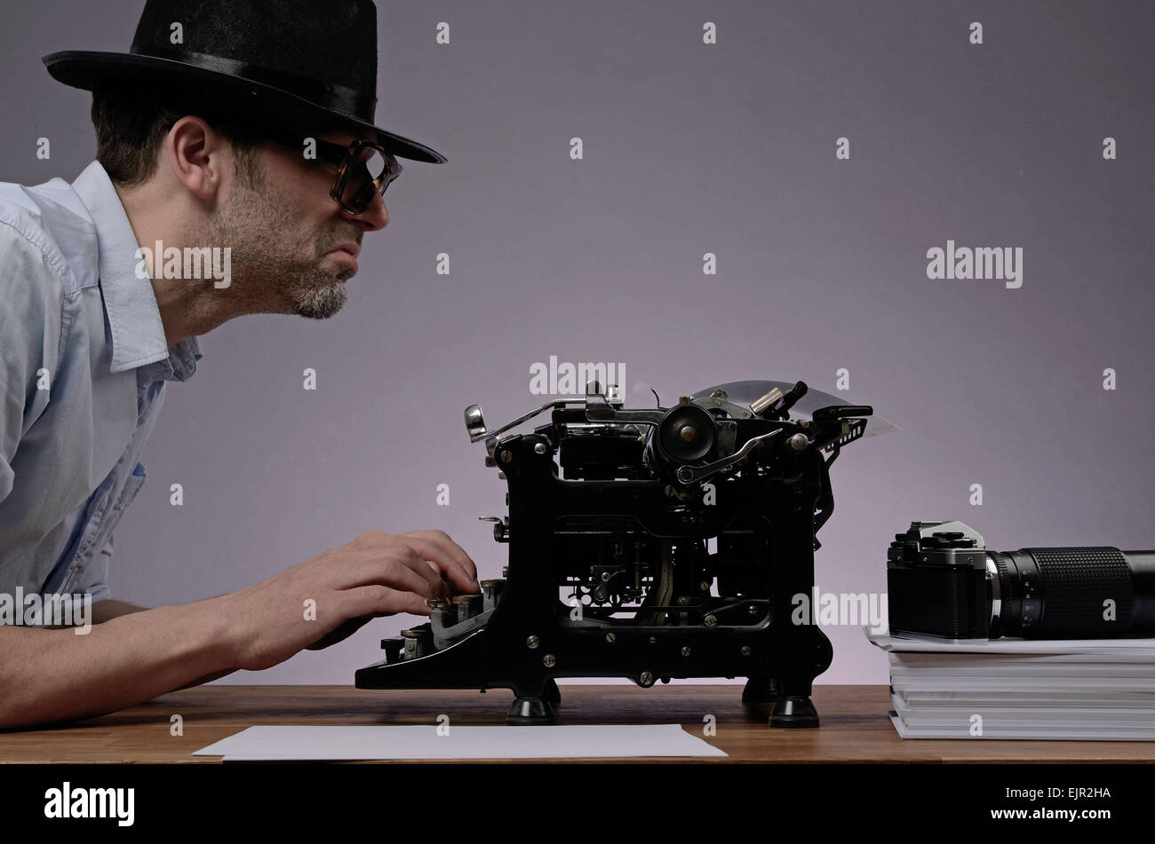 Agent with an old type writer and a vintage camera in a dark office ...
