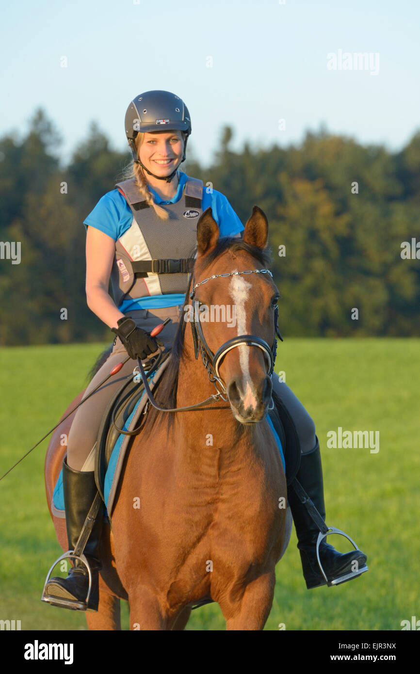Young rider wearing a helmet and a body protector on back of an Arab ...