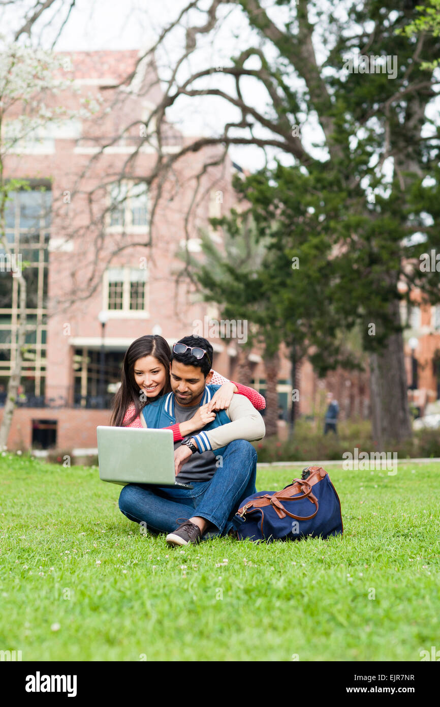 Students hugging and using laptop on campus Stock Photo - Alamy