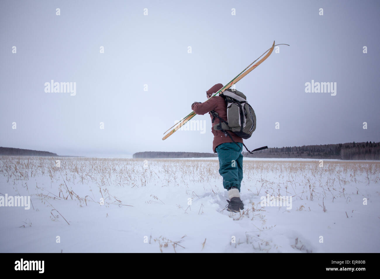 Mixed race man carrying skis in snowy field Stock Photo - Alamy