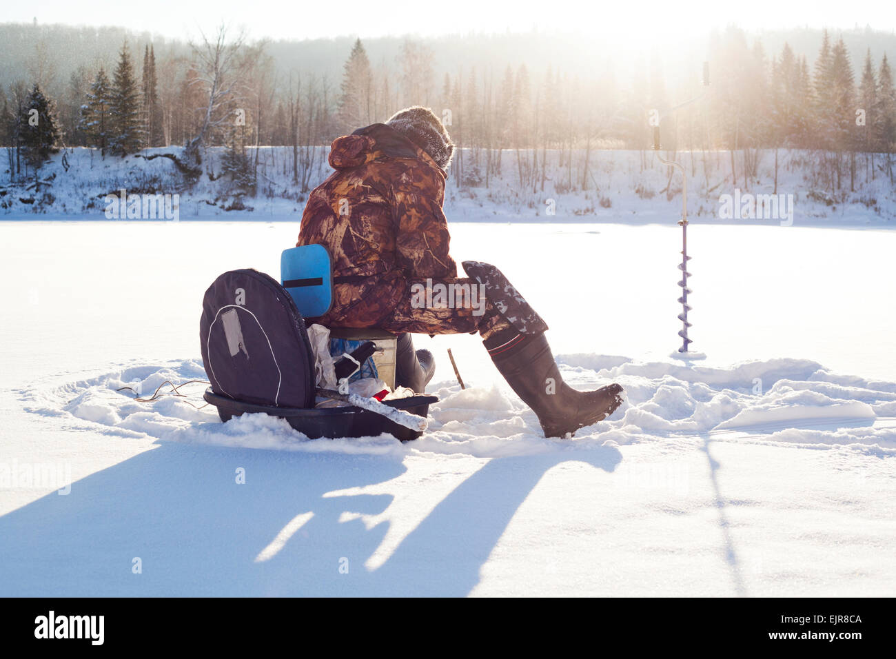 Mari man ice fishing in snowy field Stock Photo - Alamy
