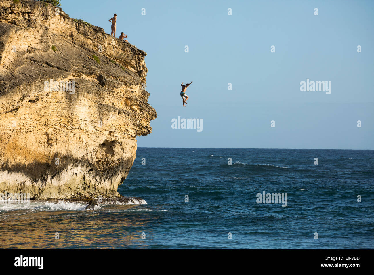 Divers jumping off cliff into ocean Stock Photo - Alamy