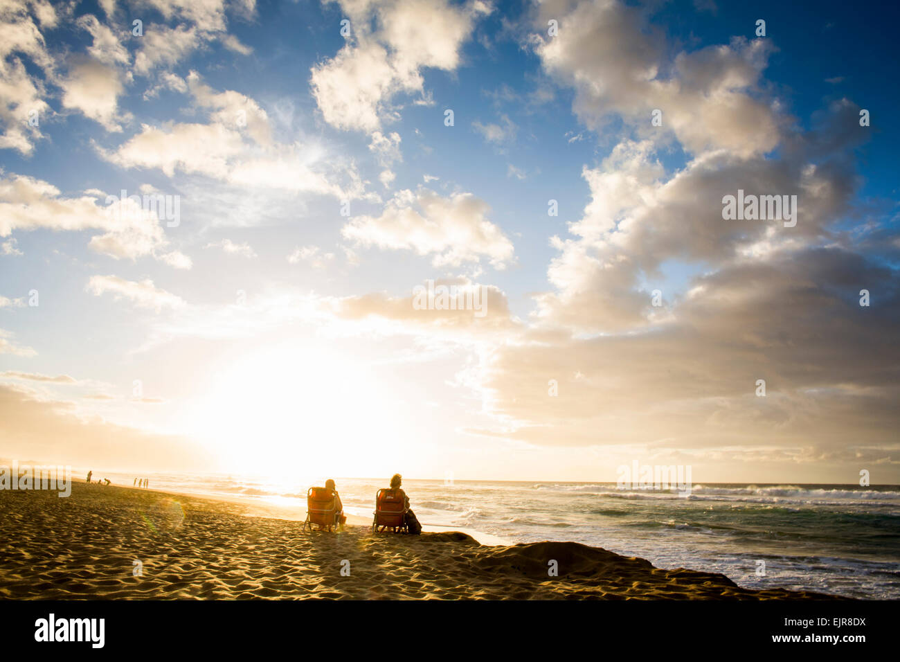 People relaxing on beach at sunrise Stock Photo - Alamy