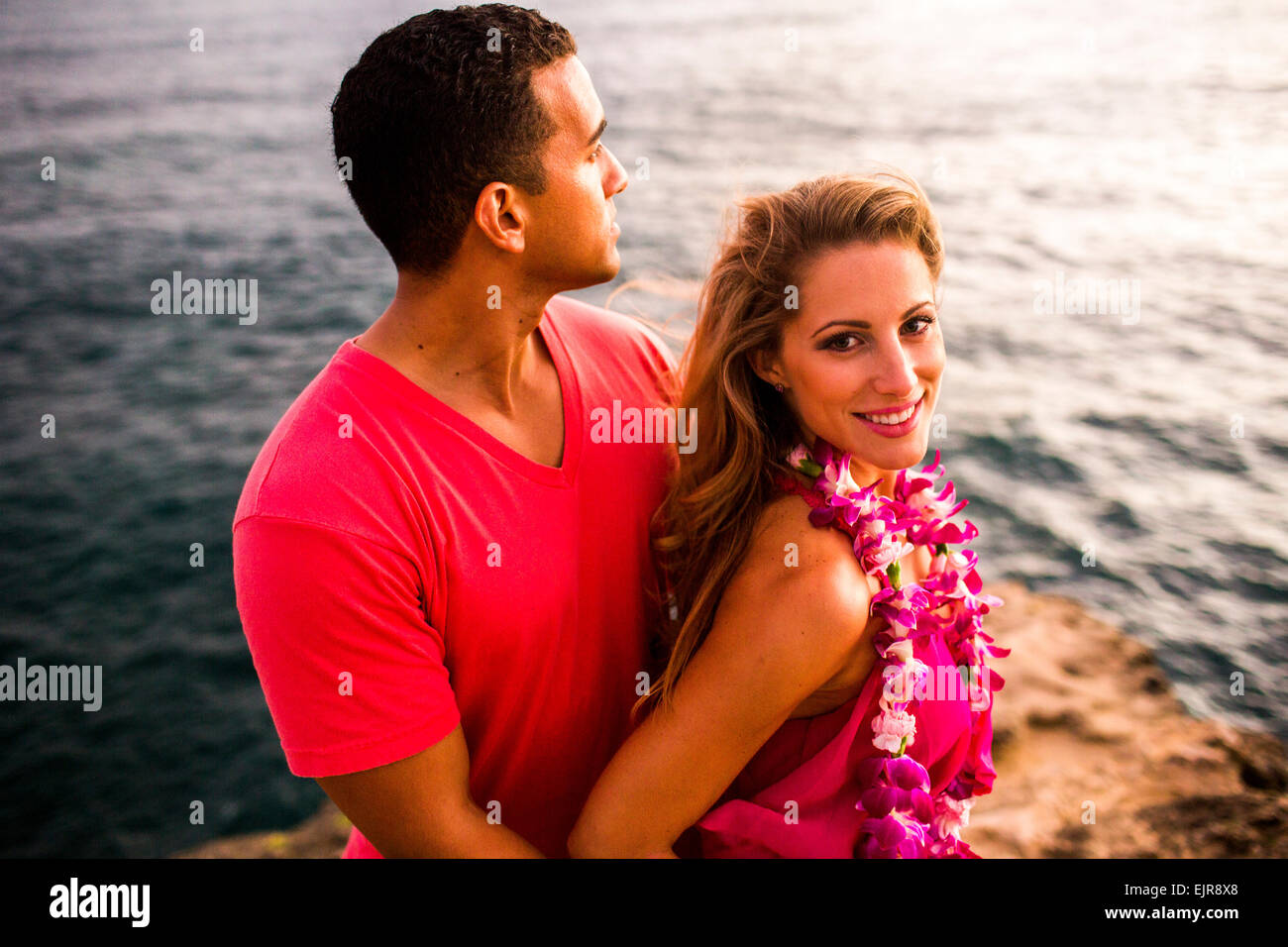 Smiling couple hugging on rocks over ocean Stock Photo - Alamy