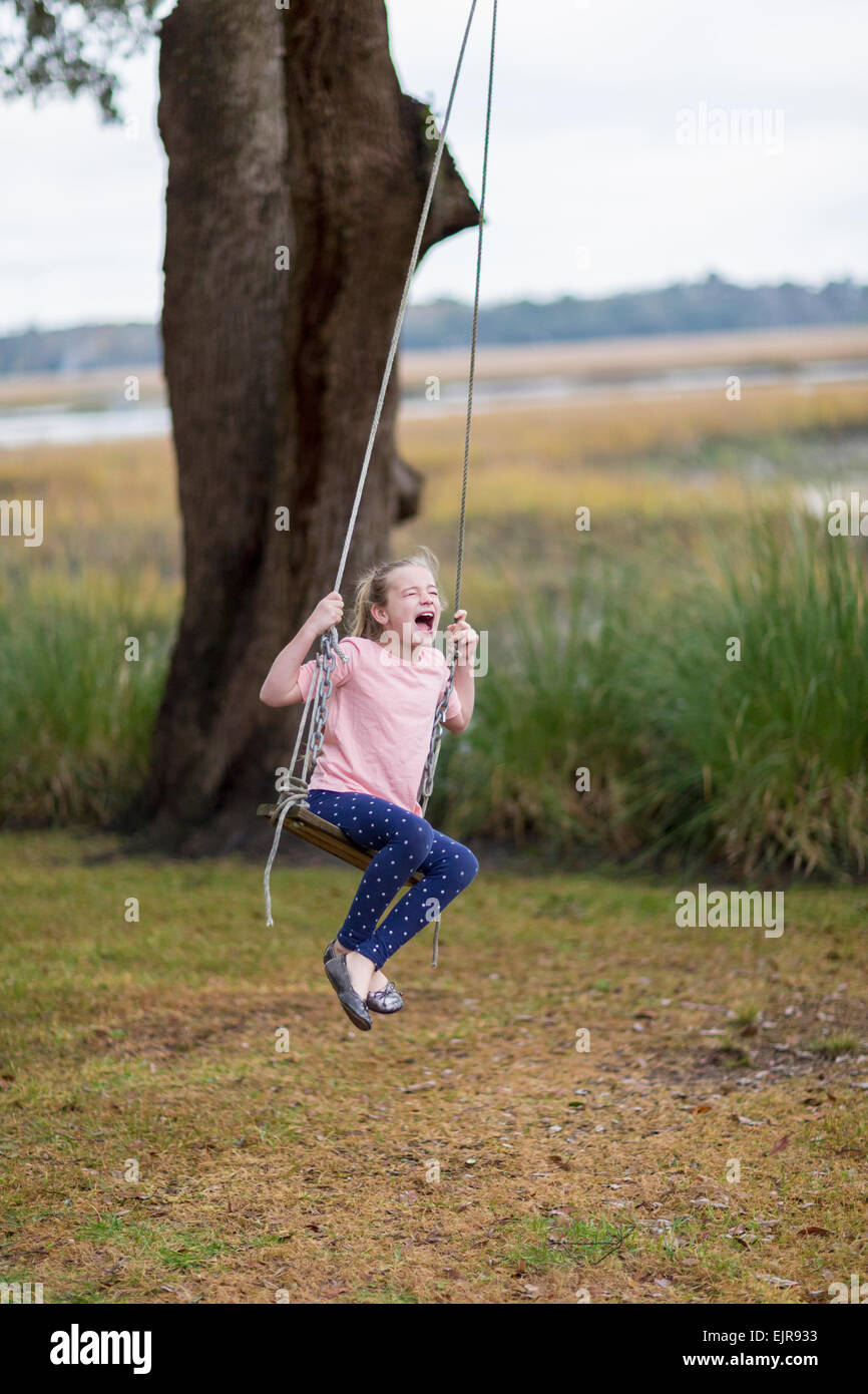 Caucasian girl playing on swing in field Stock Photo - Alamy