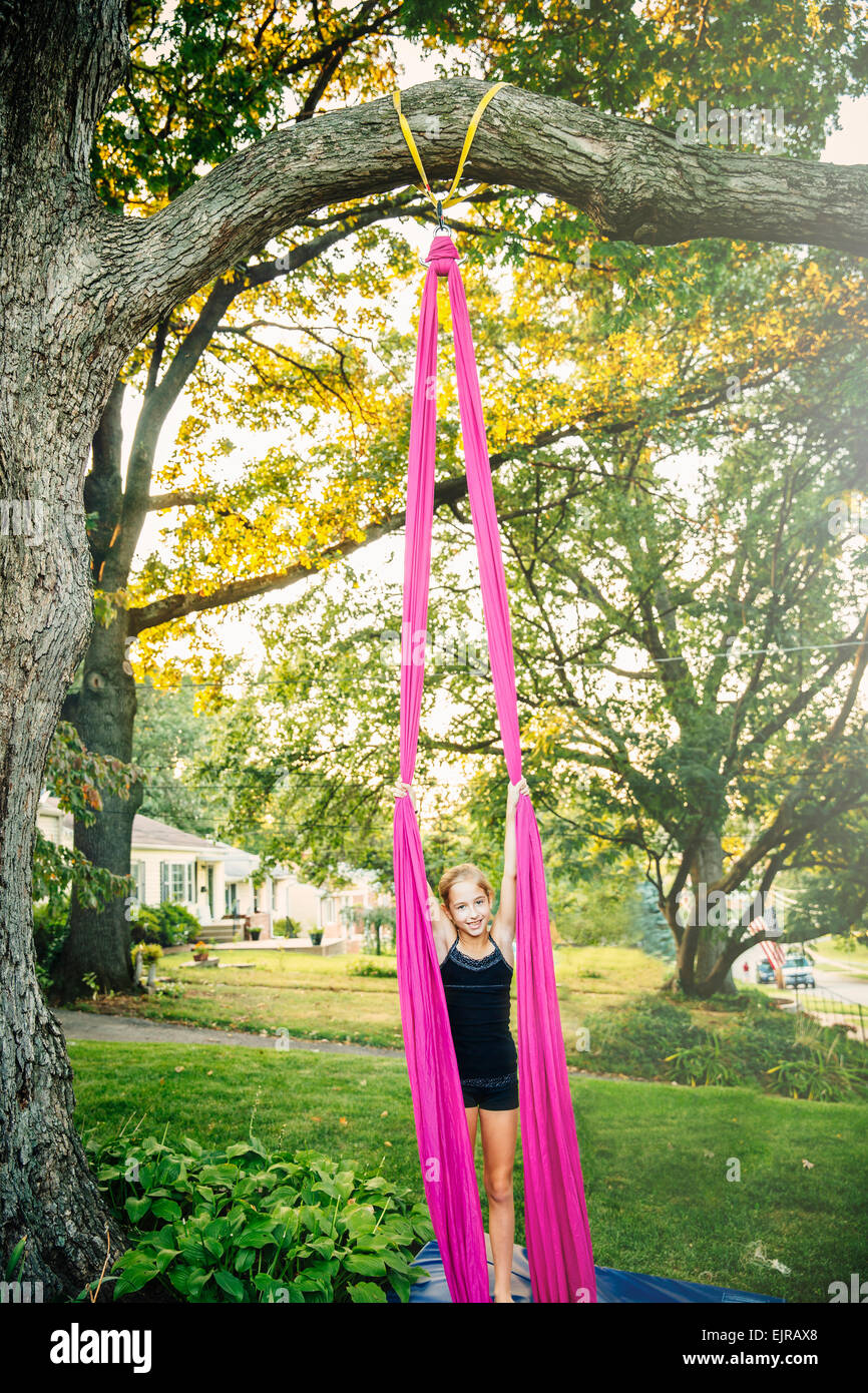 Acrobatic Caucasian girl hanging on fabric under tree Stock Photo - Alamy