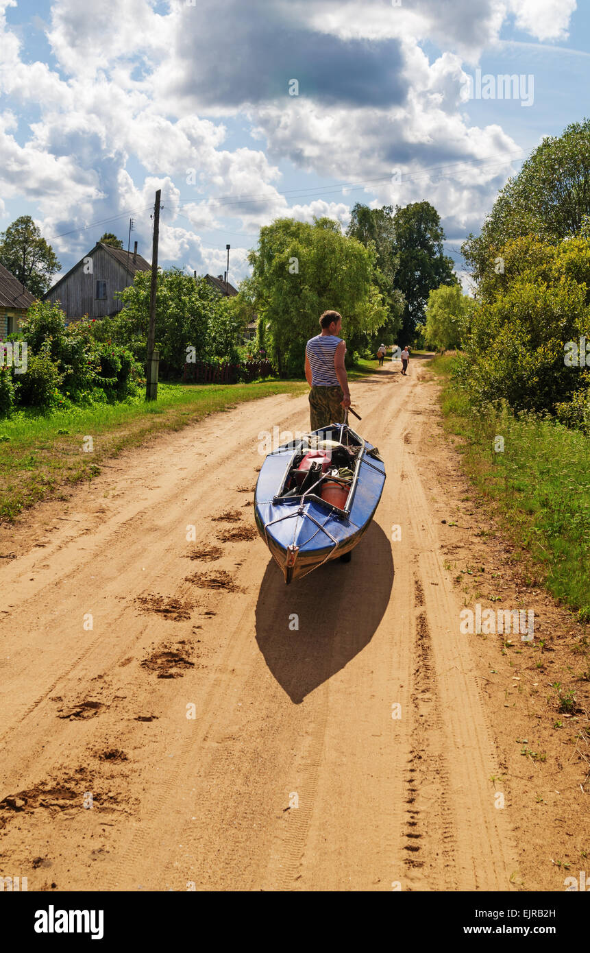 Canoe transportation on the cart on the forest road from lake to lake ...