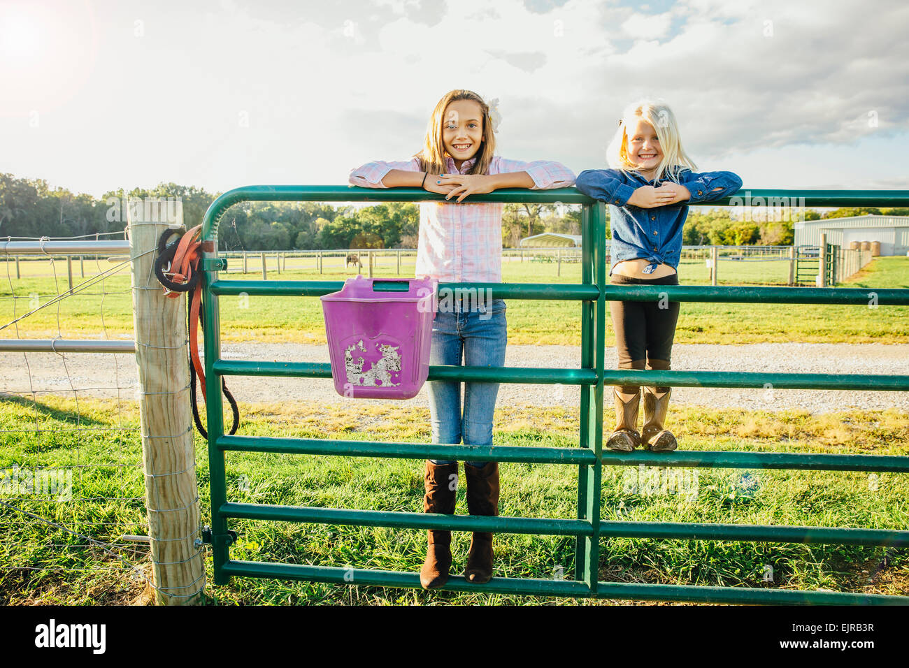 Caucasian girls standing on fence on ranch Stock Photo - Alamy