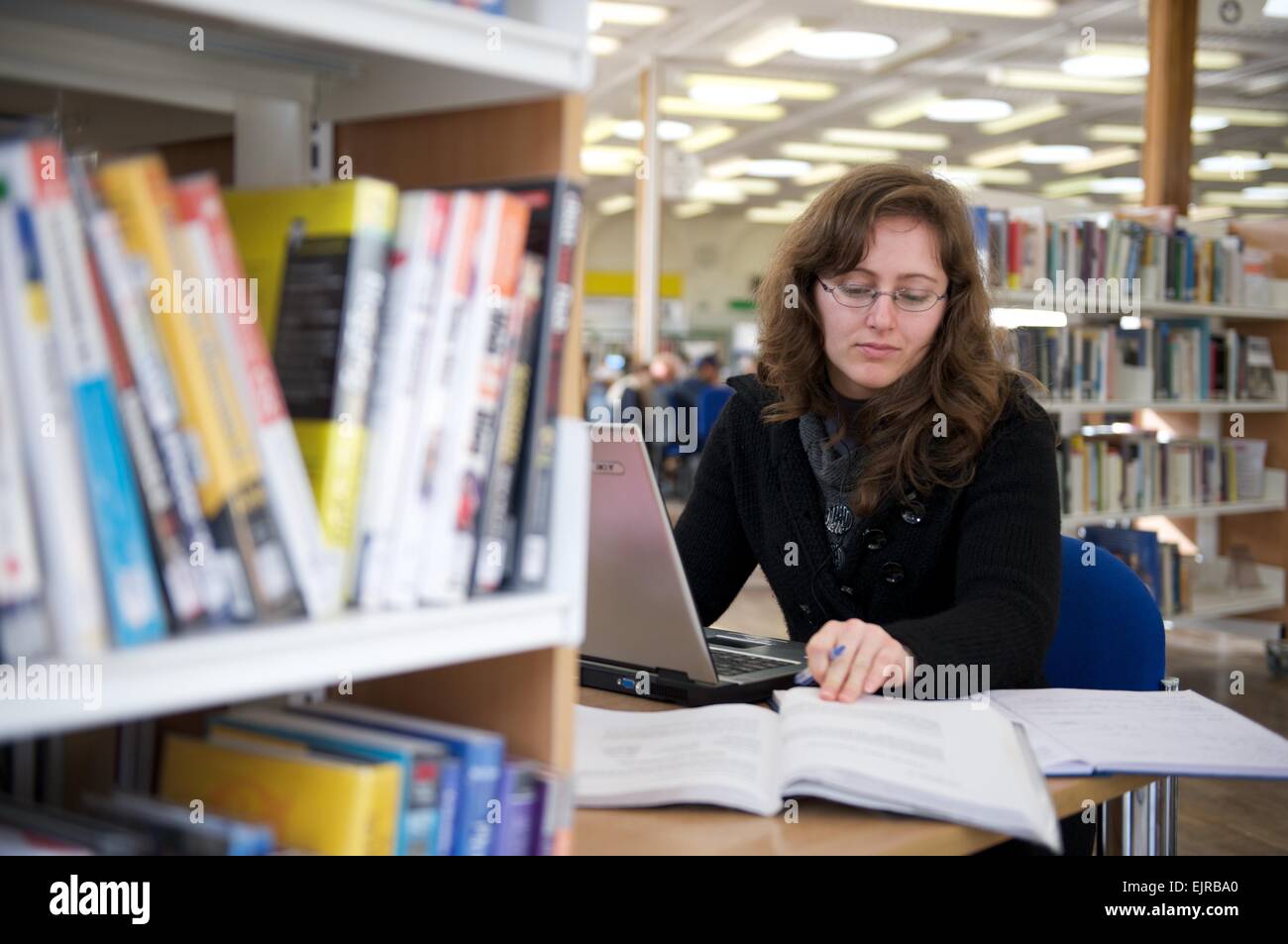 Young woman works at a desk in a public library Stock Photo - Alamy