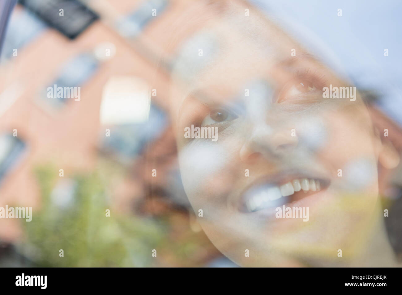 Caucasian woman and reflection of apartment buildings in window Stock ...