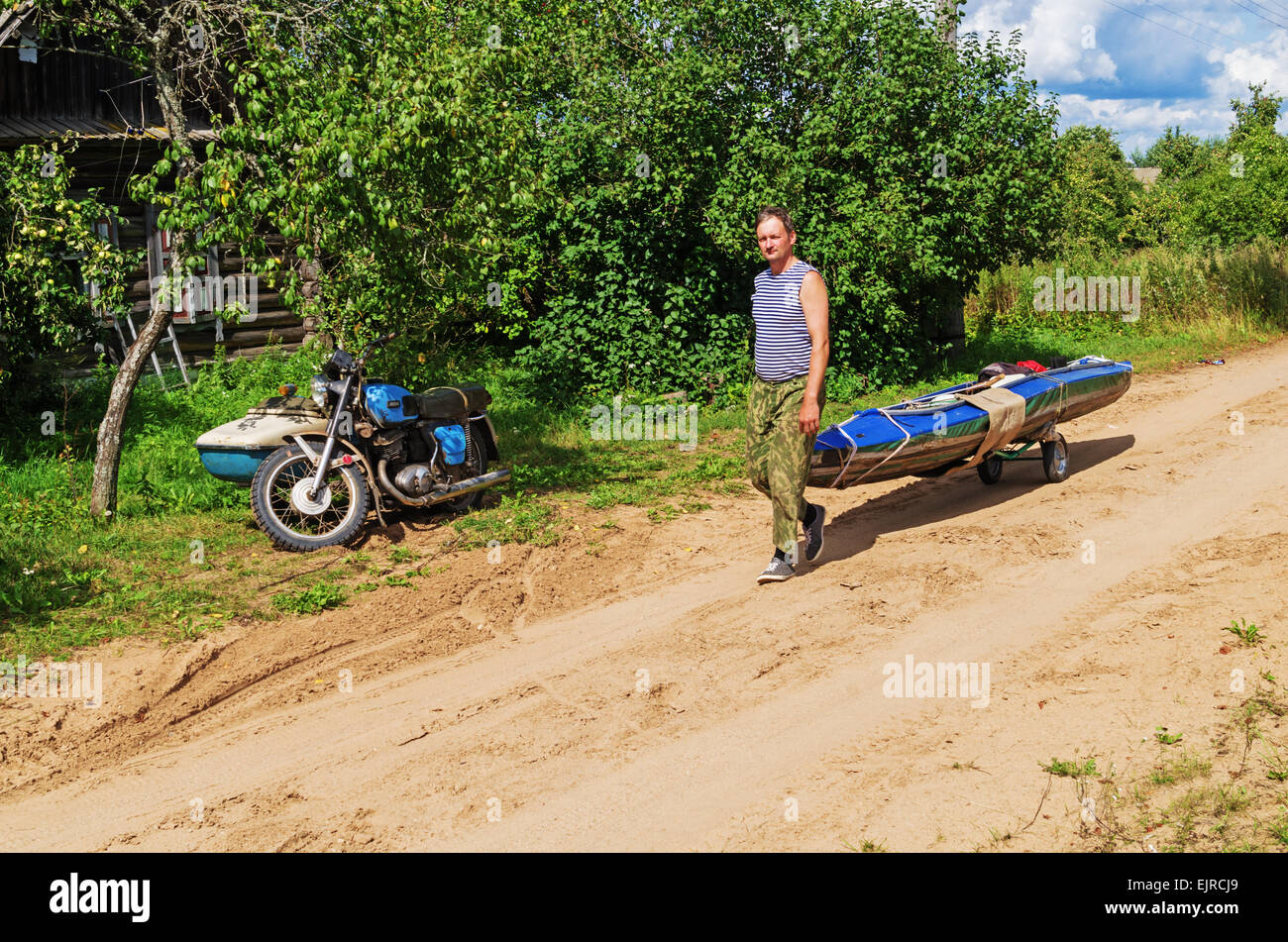 Canoe transportation on the cart on the forest road from lake to lake ...