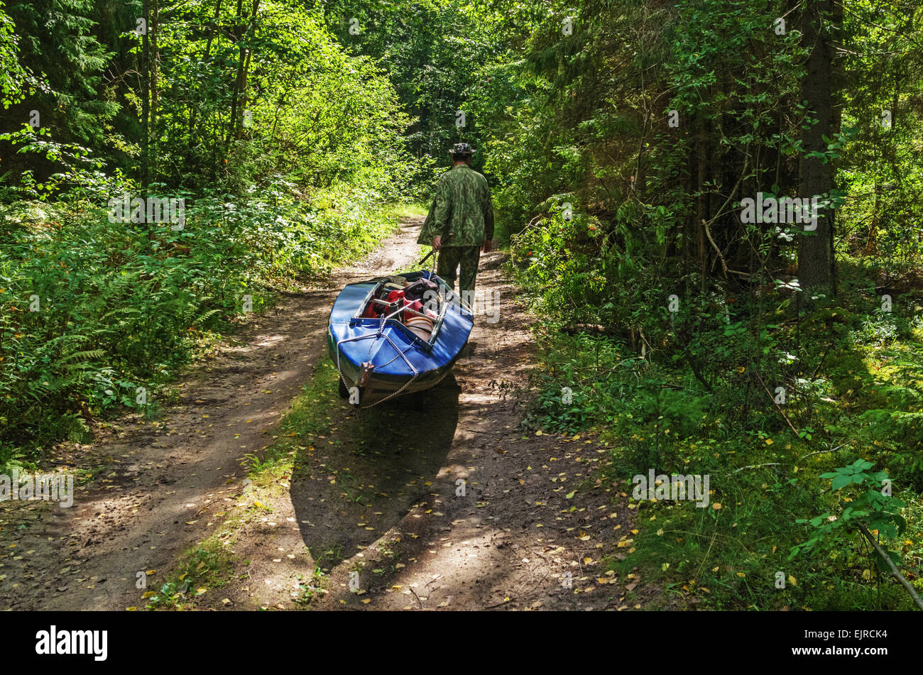 Canoe transportation on the cart on the forest road from lake to lake ...
