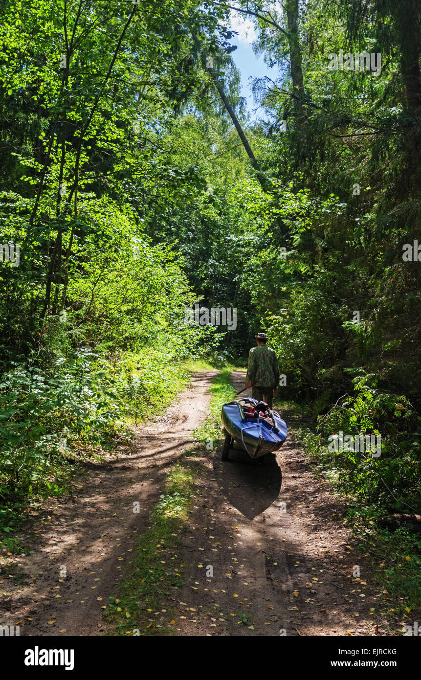 Canoe transportation on the cart on the forest road from lake to lake ...
