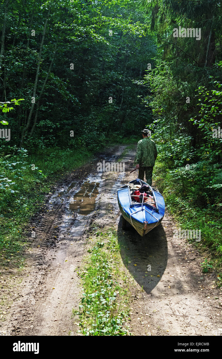 Canoe transportation on the cart on the forest road from lake to lake ...