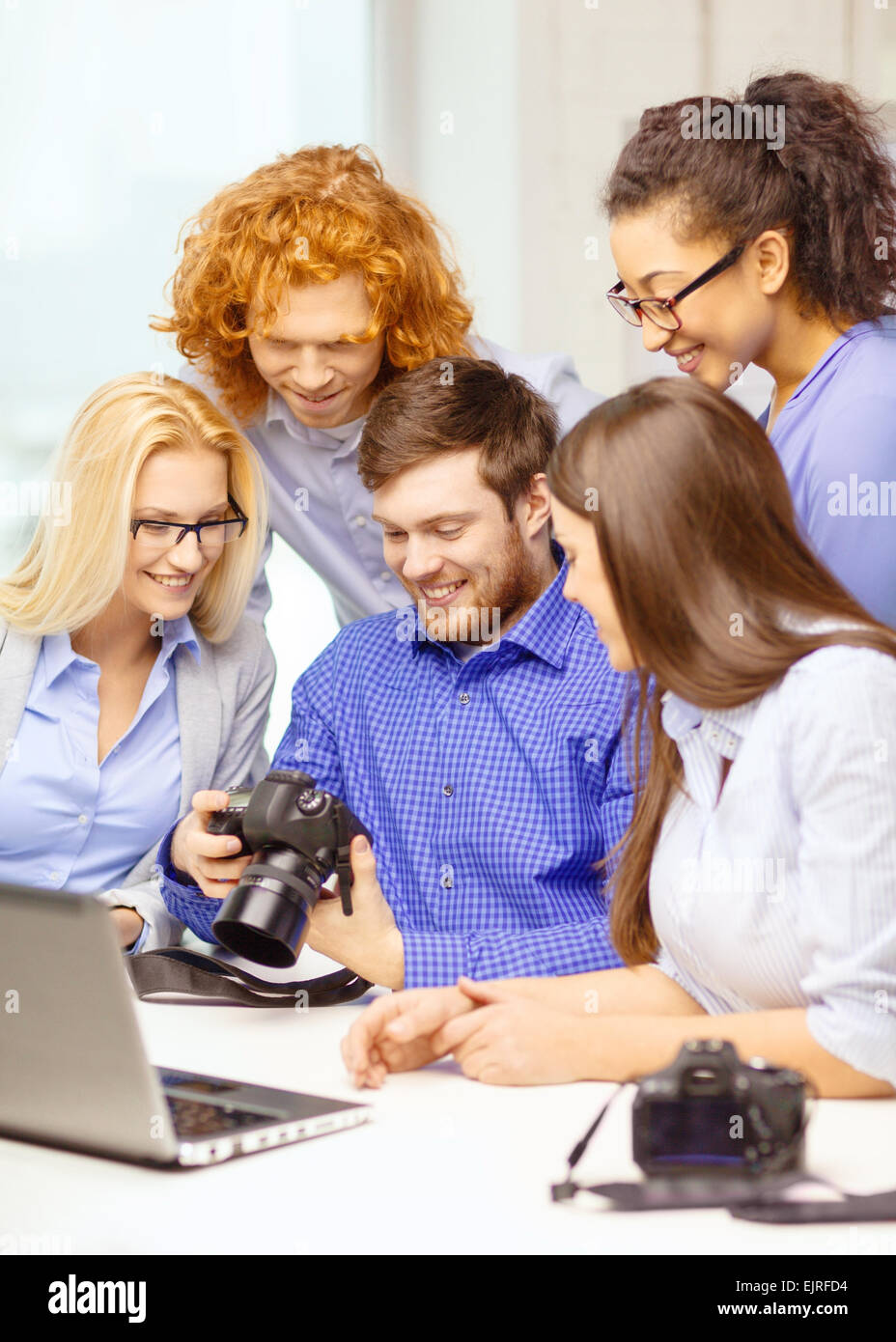 smiling team with laptop and photocamera in office Stock Photo - Alamy