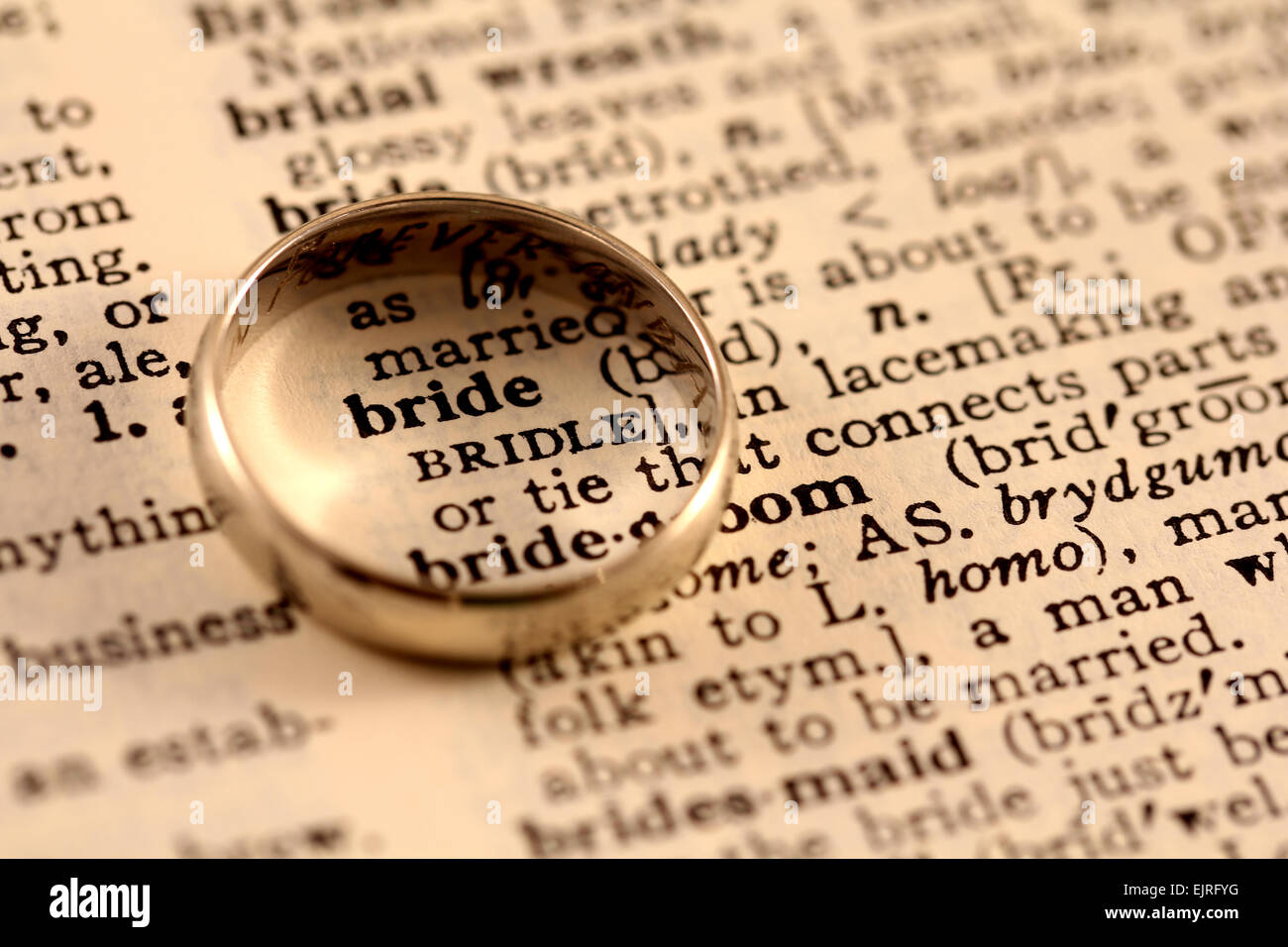 A wedding band sits atop the word bride in the dictionary, circling it ...