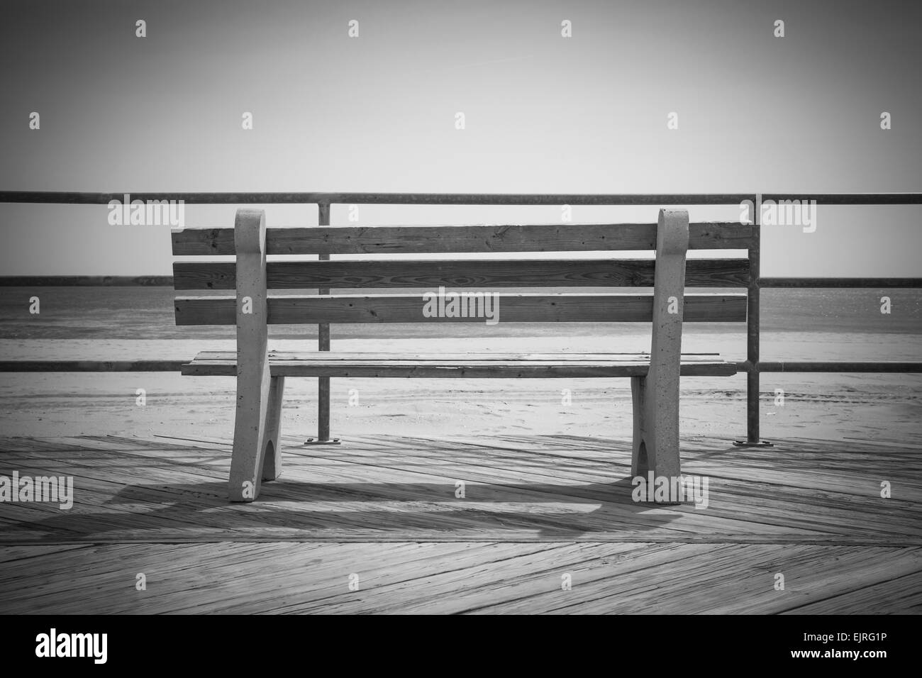 A bench on a seaside boardwalk overlooking the ocean; horizontal format ...