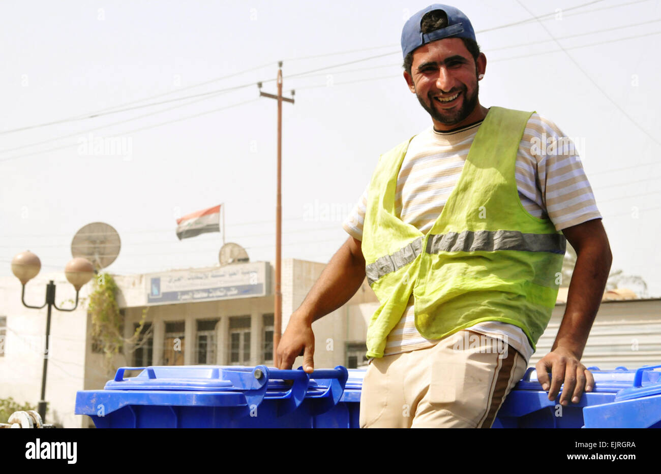 A city worker prepares to unload new trash containers from a truck and ...
