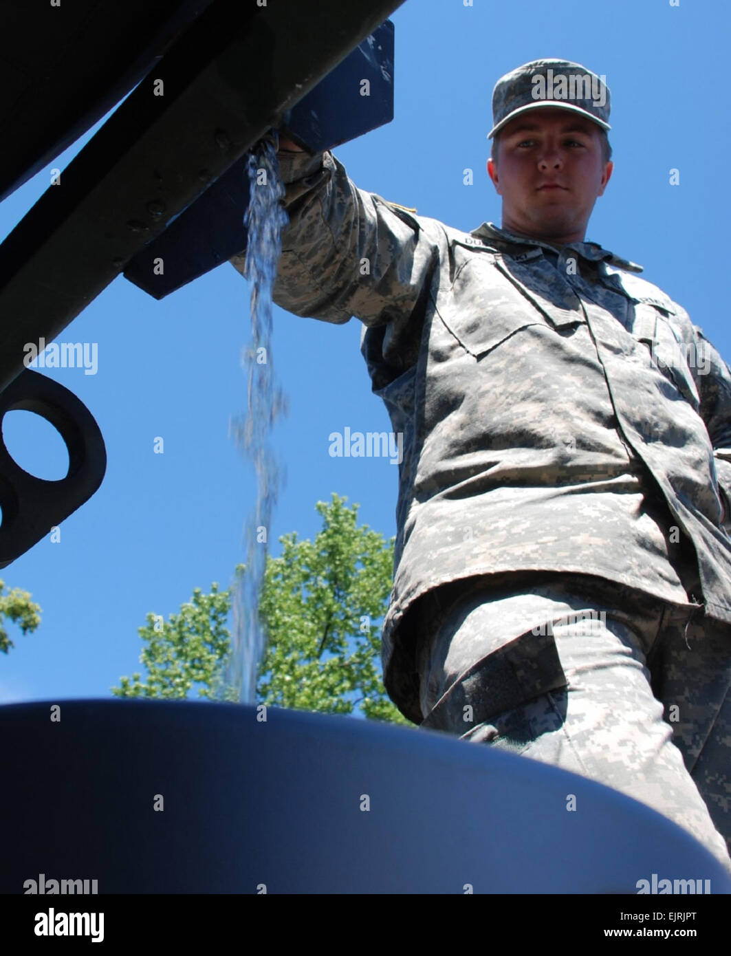 Indiana Army National Guard Spc. Daniel Dubowski dispenses water into a ...