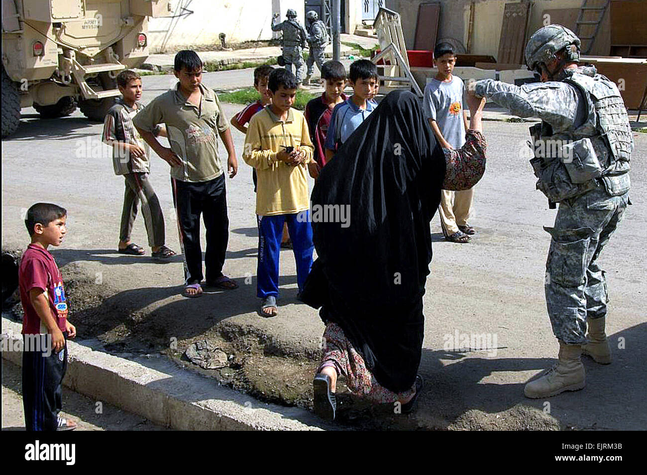 Staff Sgt. Jon Anderstrom helps an elderly Iraqi woman cross a curb ...