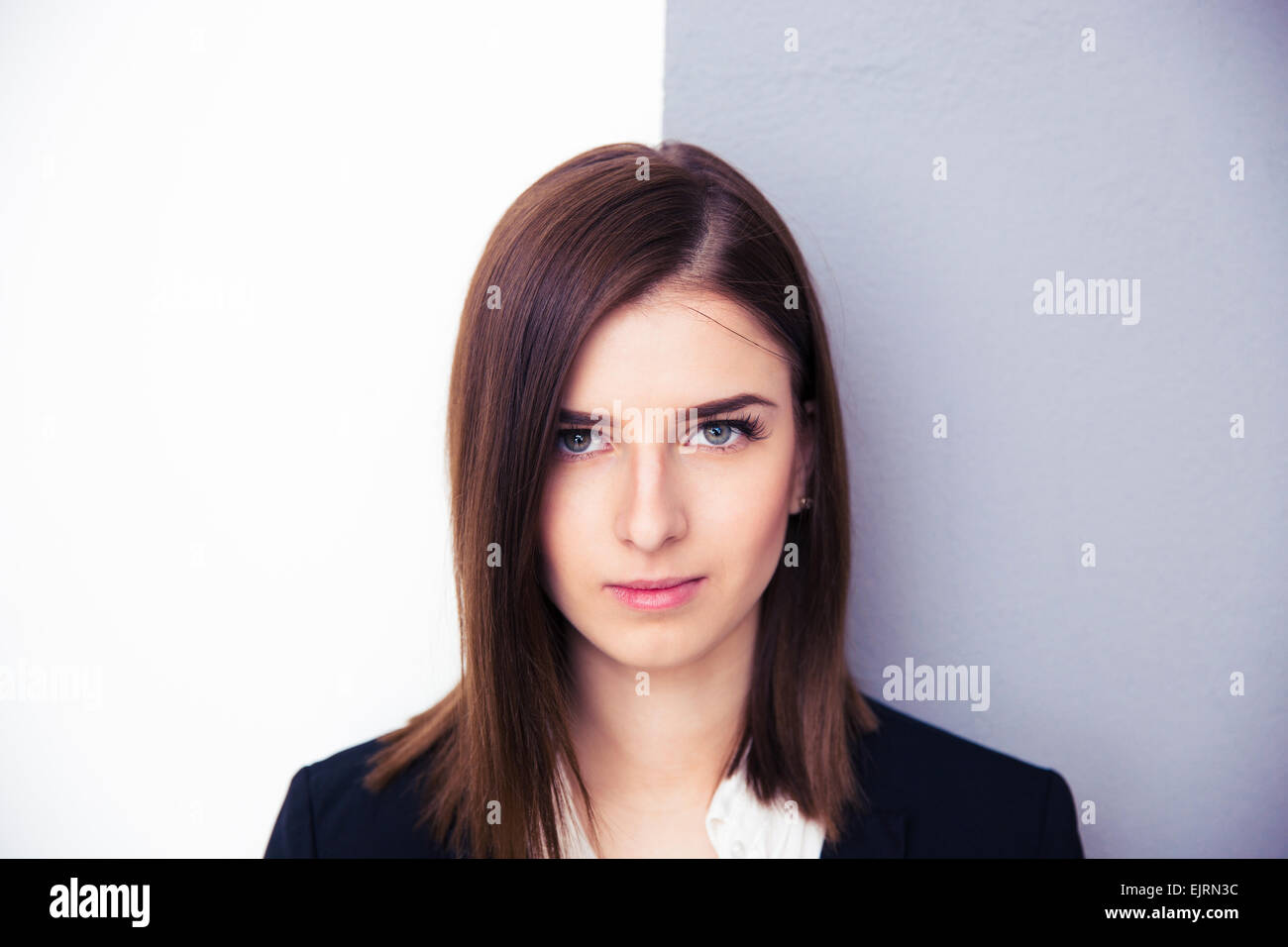 Portrait of a cute young businesswoman standing over half white and ...