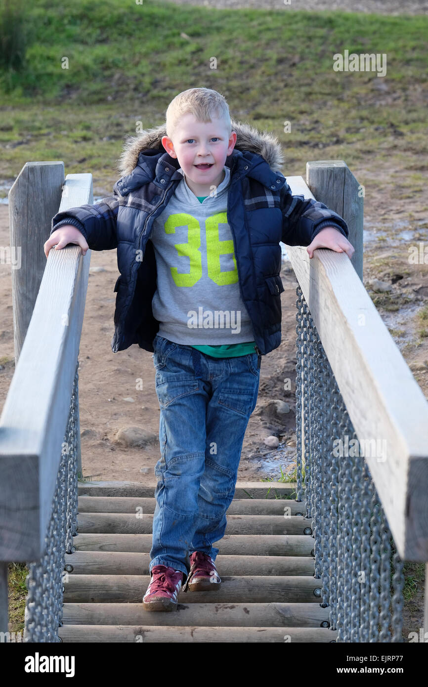 Boy aged six crossing a wooden bridge at Brockholes nature reserve near ...