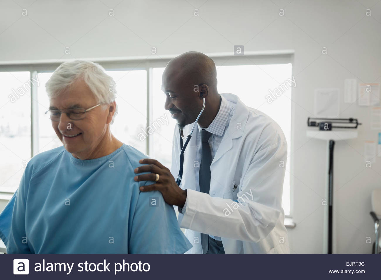 Doctor checking senior mans back in examination room Stock Photo - Alamy