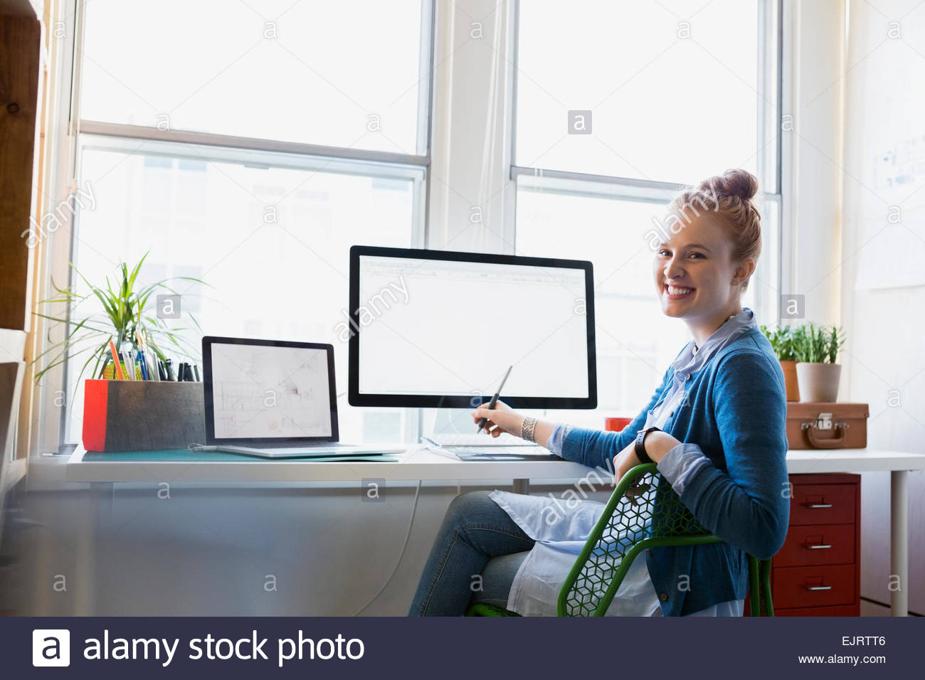 Portrait of smiling designer at computer in office Stock Photo - Alamy