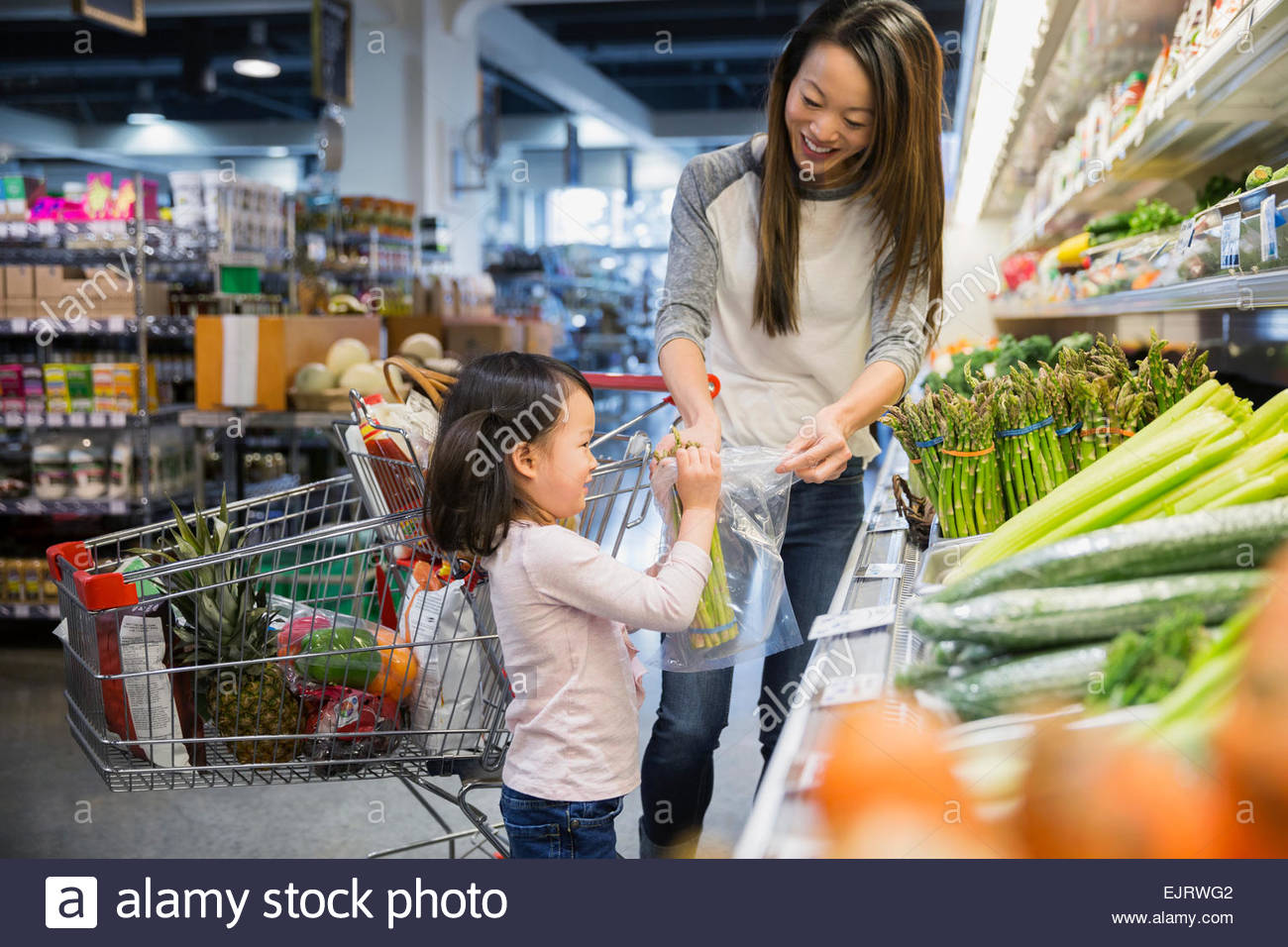 Mother and daughter bagging asparagus in grocery store Stock Photo - Alamy
