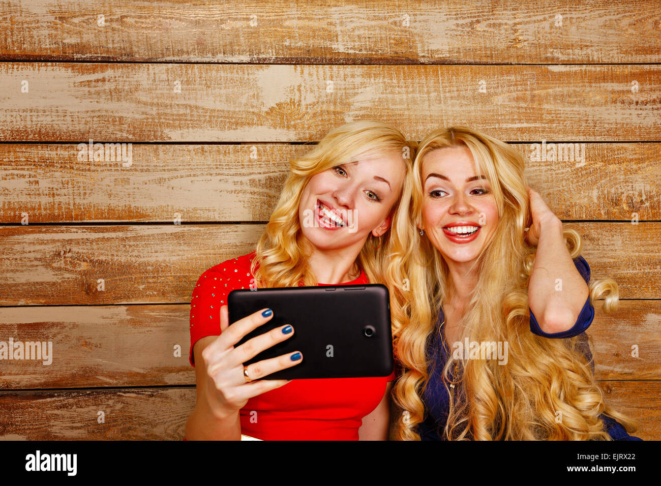 Young sisters with long blonde hair, make selfie on the tablet PC. Girl ...