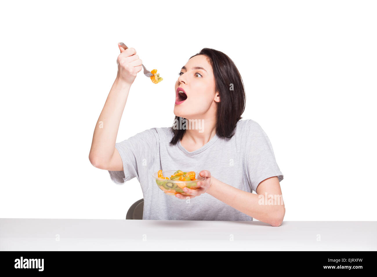 natural woman eating healthy food with orange and kiwi on white ...