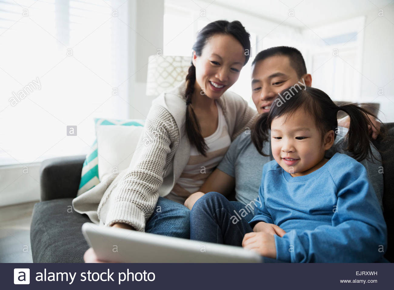 Family using digital tablet on sofa Stock Photo - Alamy