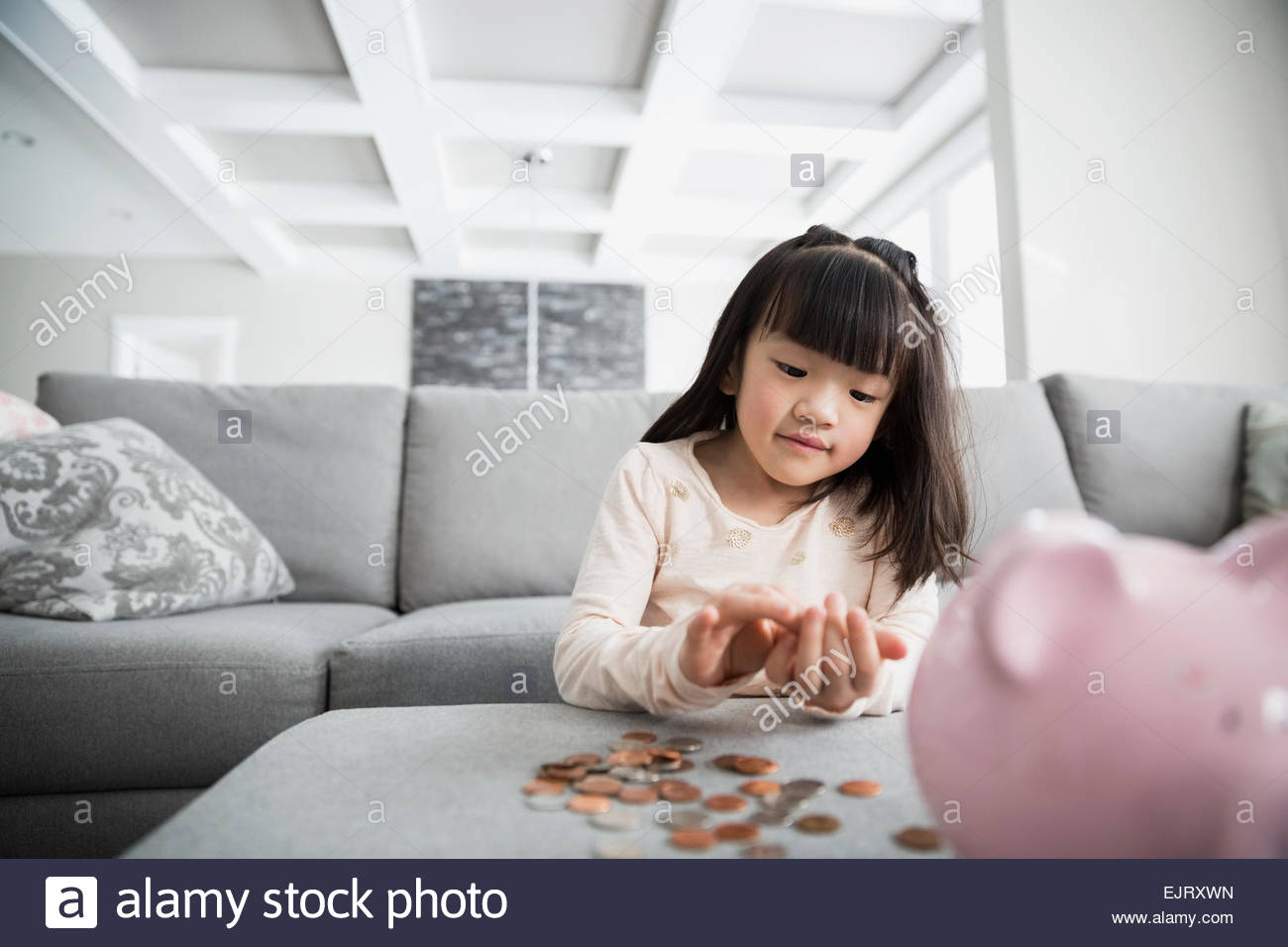 Girl counting coins from piggy bank in living room Stock Photo - Alamy