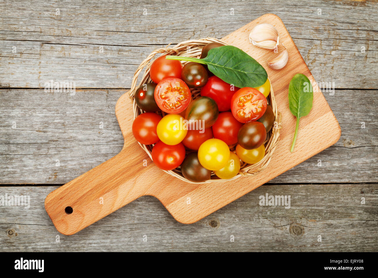 Colorful cherry tomatoes on cutting board over wooden table background ...