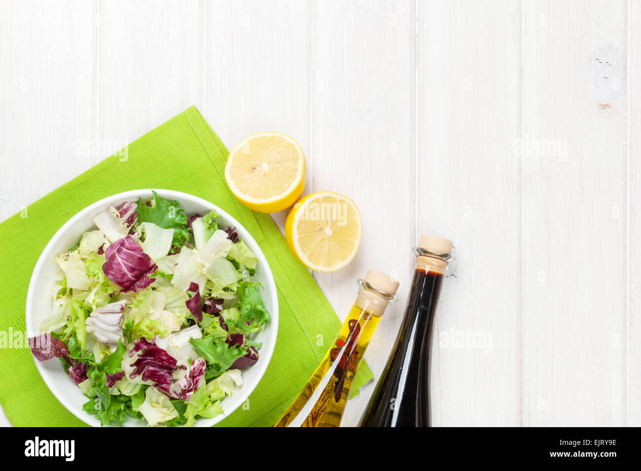Fresh healthy salad and condiments over white wooden table. View from ...