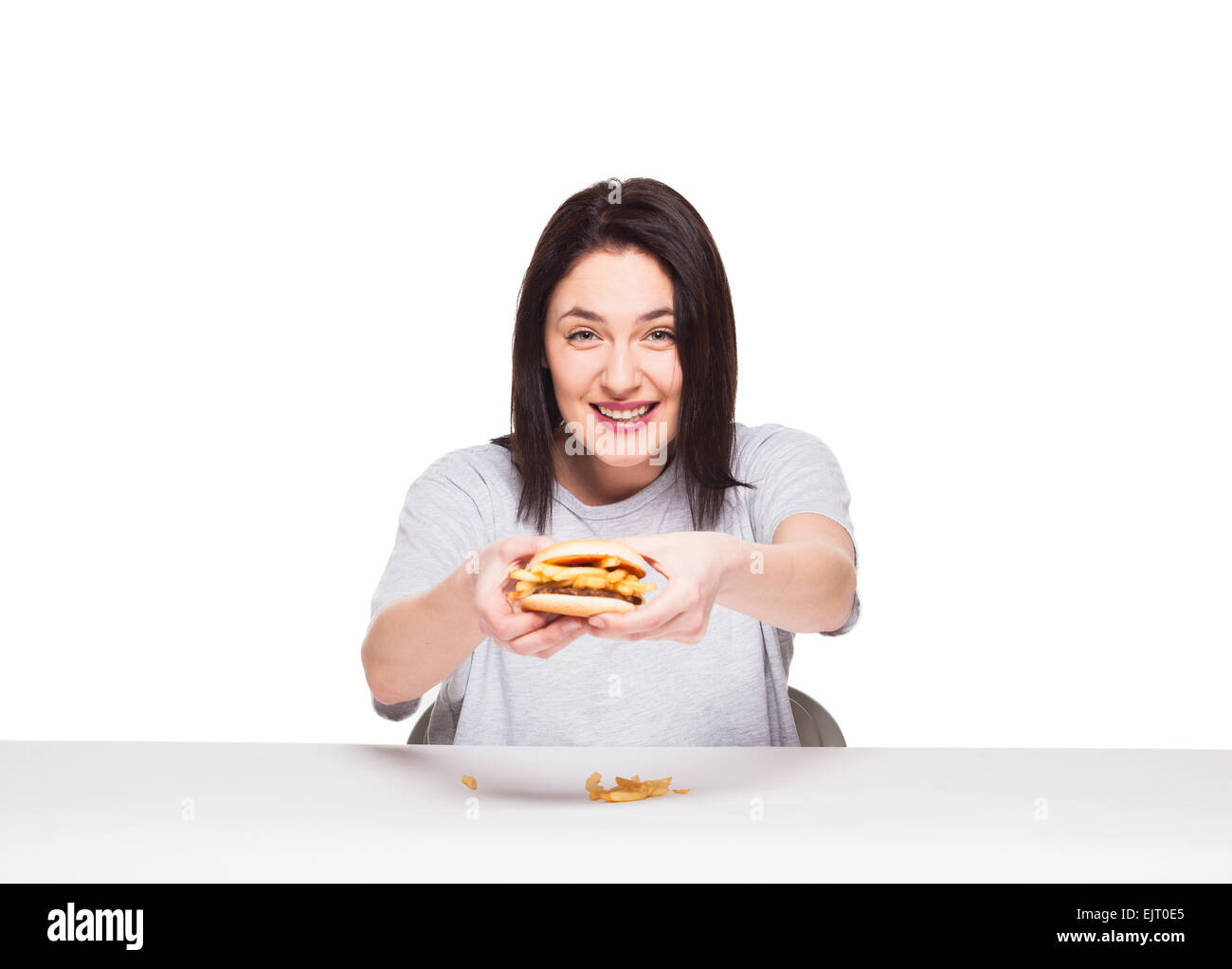 young natural woman eating junk food, hamburger and fries, on white ...