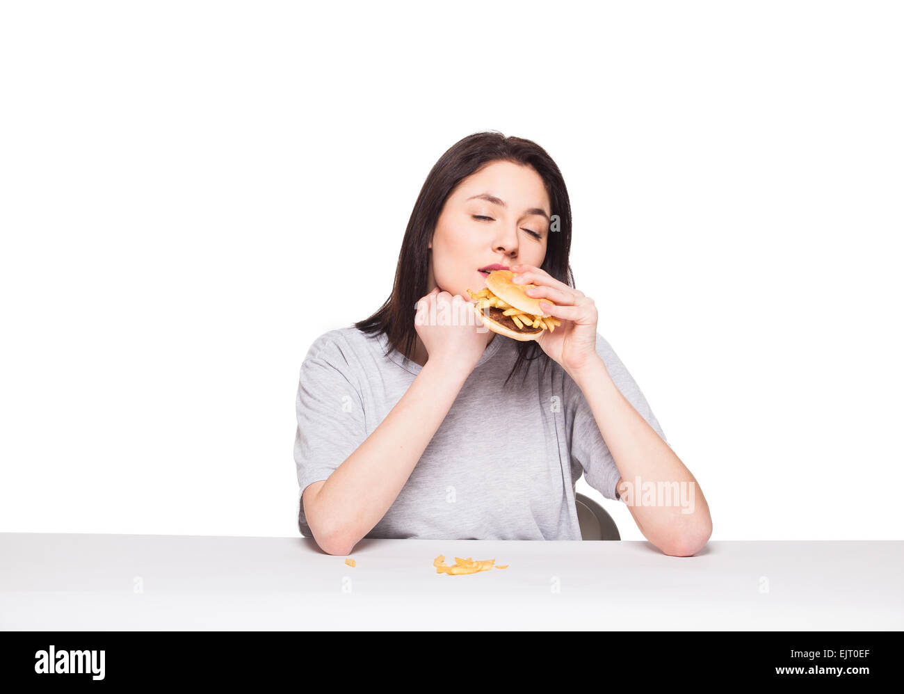 young natural woman eating junk food, hamburger and fries, on white ...