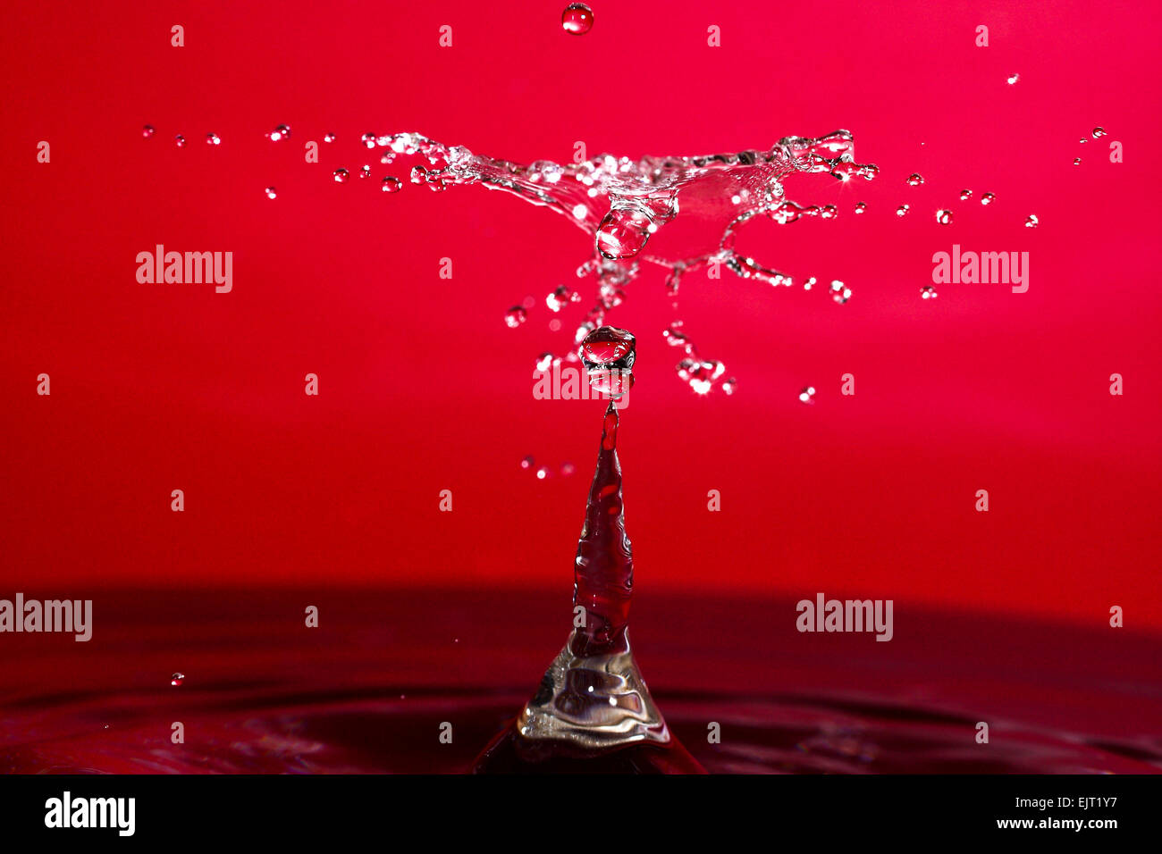 Water drop collisions with a red background Stock Photo - Alamy