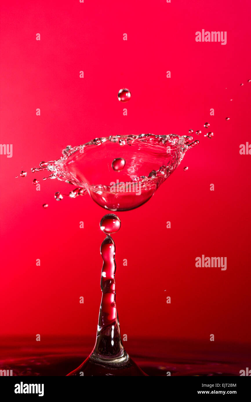 Water drop collisions with a red background Stock Photo - Alamy